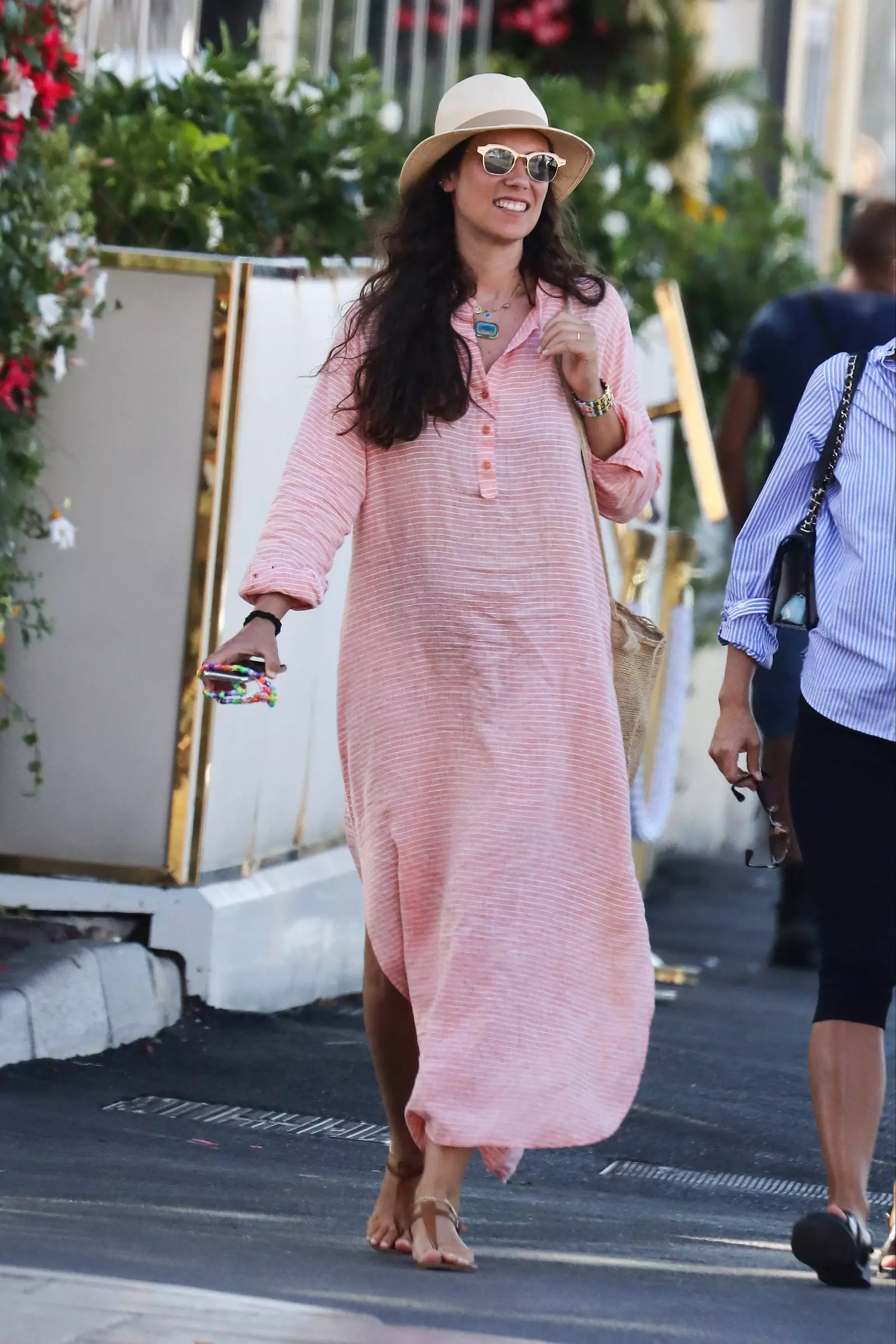 Tatiana Santo Domingo mal-wasla tagħha f'Saint Tropez liebsa caftan strixxat sabiħ u kappell ta' xifer wiesa'.