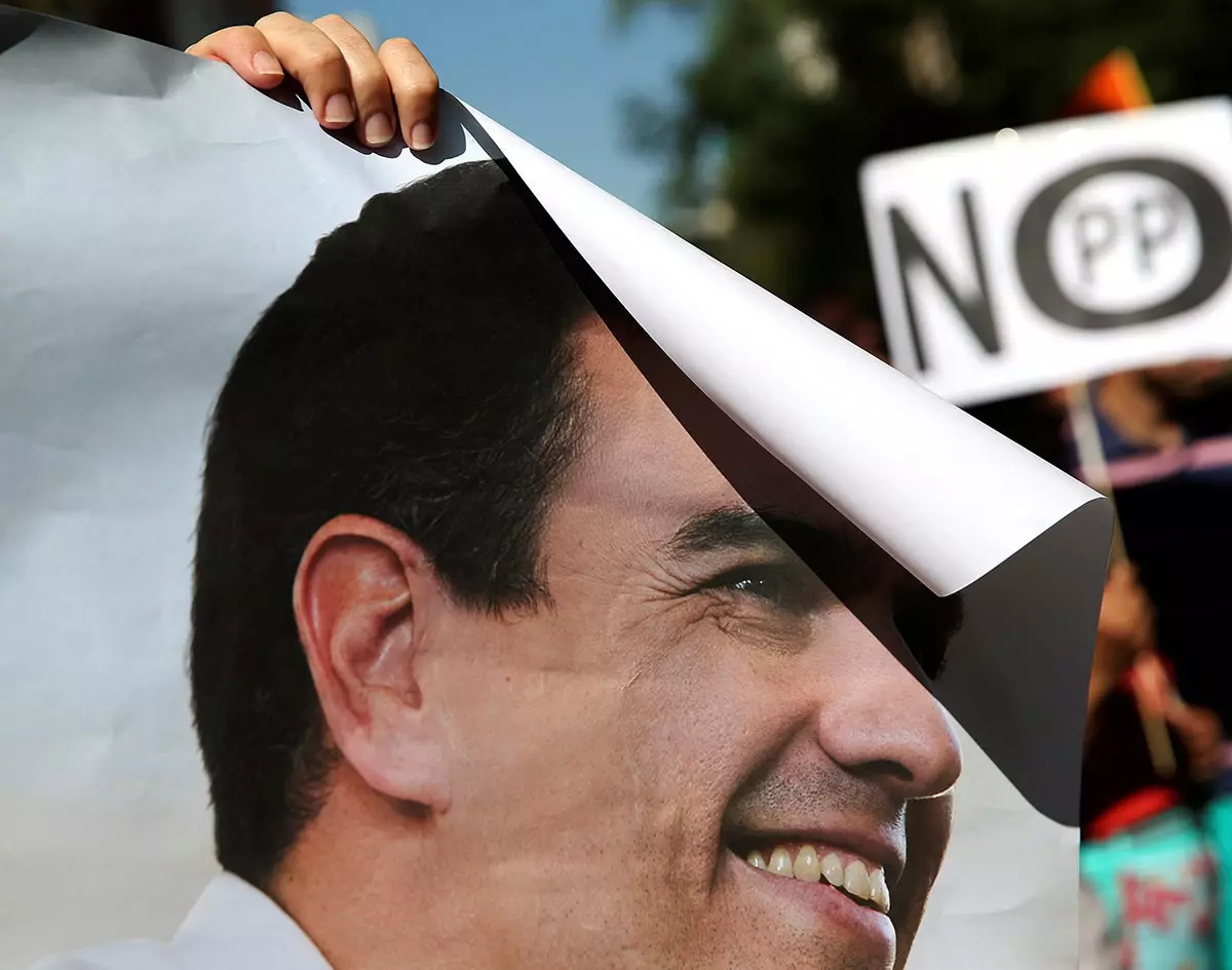 E Supporter vum Pedro Sánchez hält eng Affiche mat sengem Gesiicht ausserhalb vum PSOE Sëtz zu Ferraz.