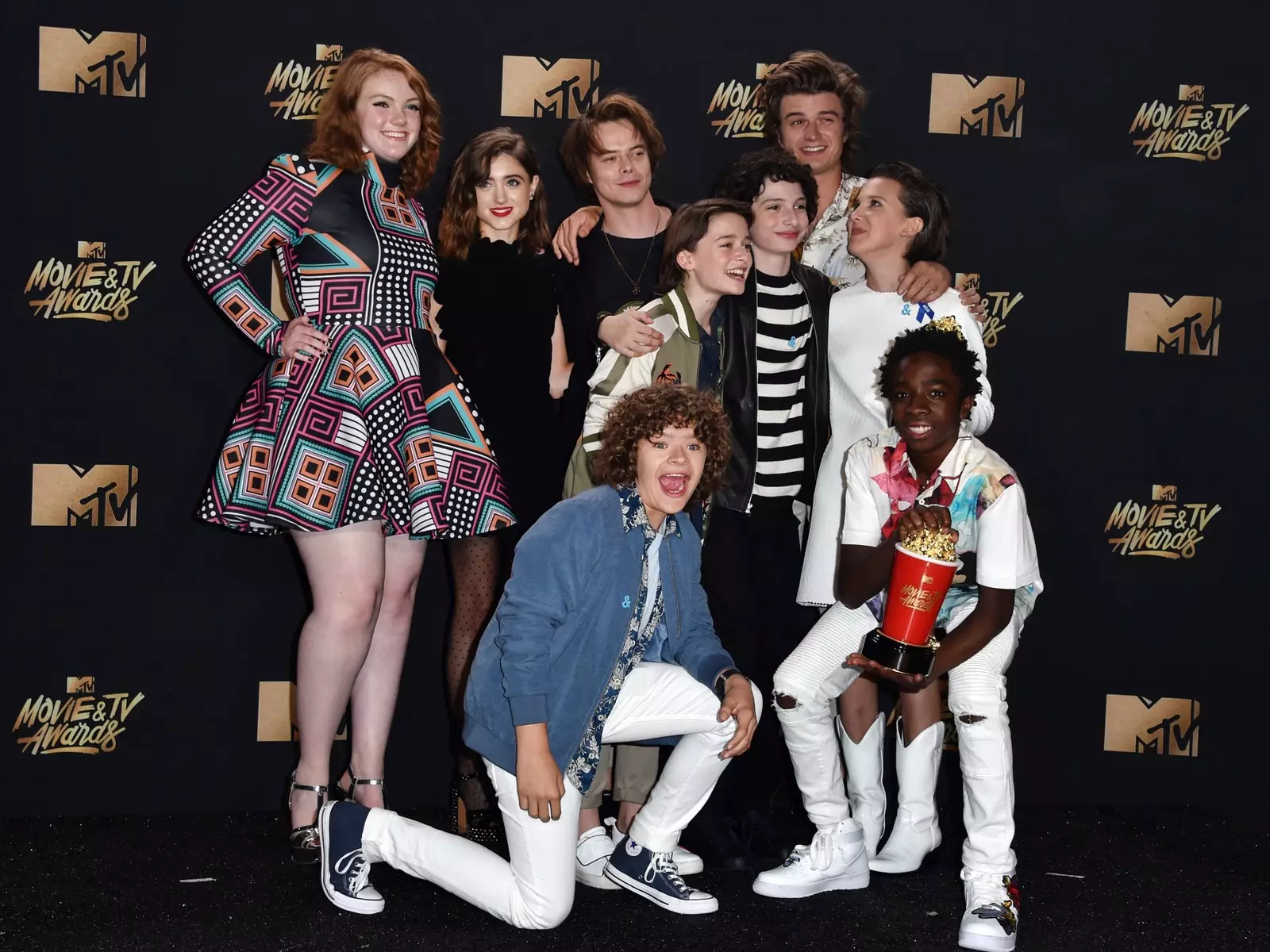 Natalia Dyer lan Charlie Heaton nganggo klambi ireng karo wong lanang liyane saka Stranger Things.