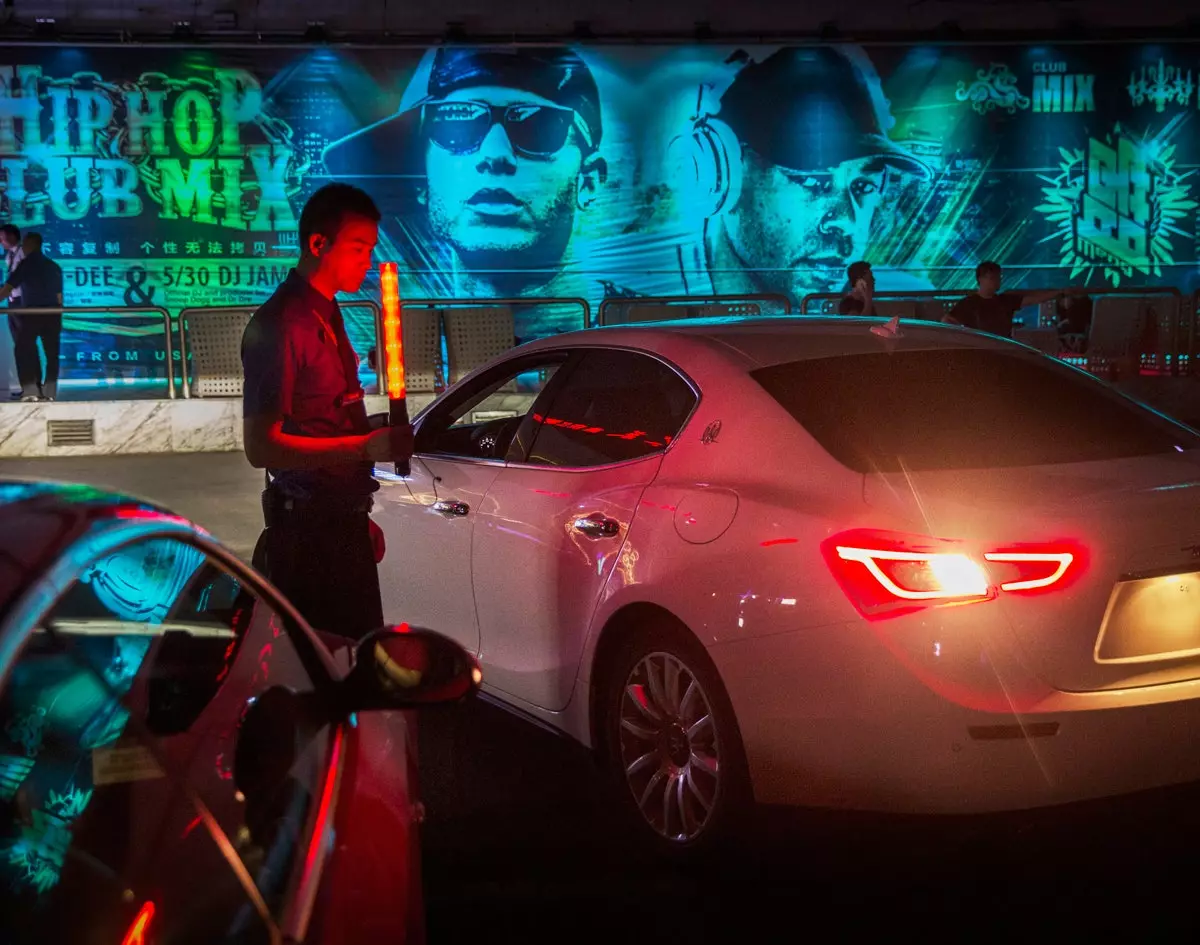 Un agent de sécurité aide à garer une voiture devant un club exclusif de Pékin en mai 2015.