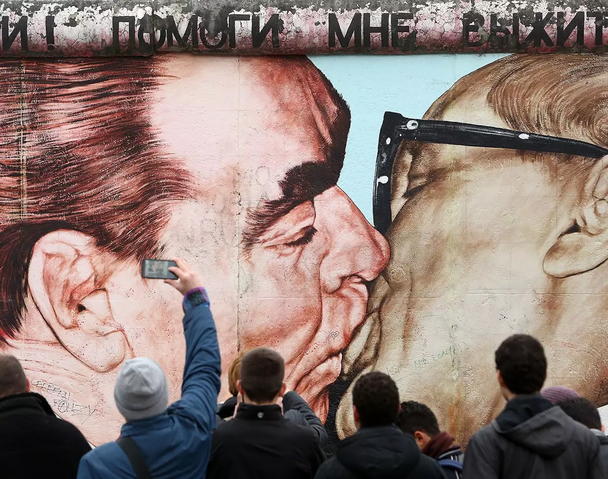 O tagata tafafao maimoa e pu'eina ata o le anti-homophobia graffiti i luga o le Berlin Wall.