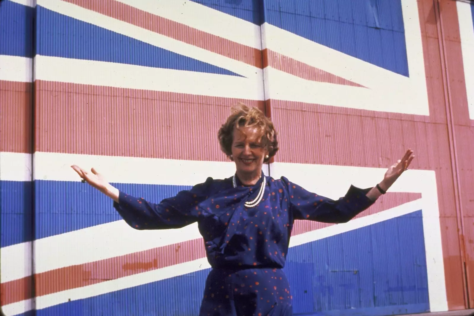 Margaret Thatcher kwụ n'elu Isle of Wight n'ihu nnukwu Union Jack nke Britain.