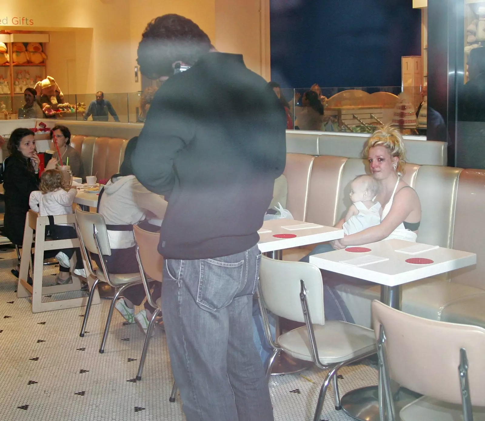 Britney græder med sin søn, mens nogle af de tilstedeværende mødre i lokalerne observerer hende.