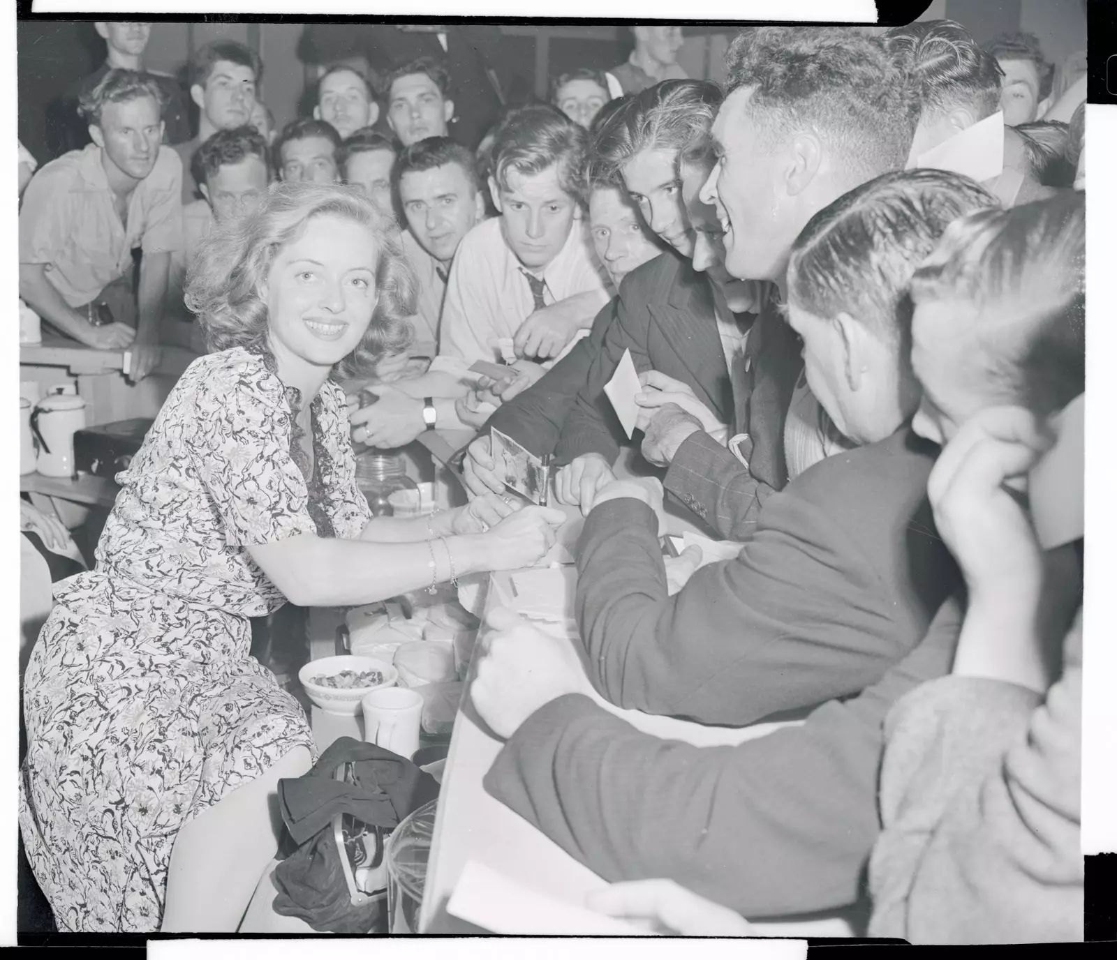 Bette Davis surrounded by Marines at the Hollywood Canteen.