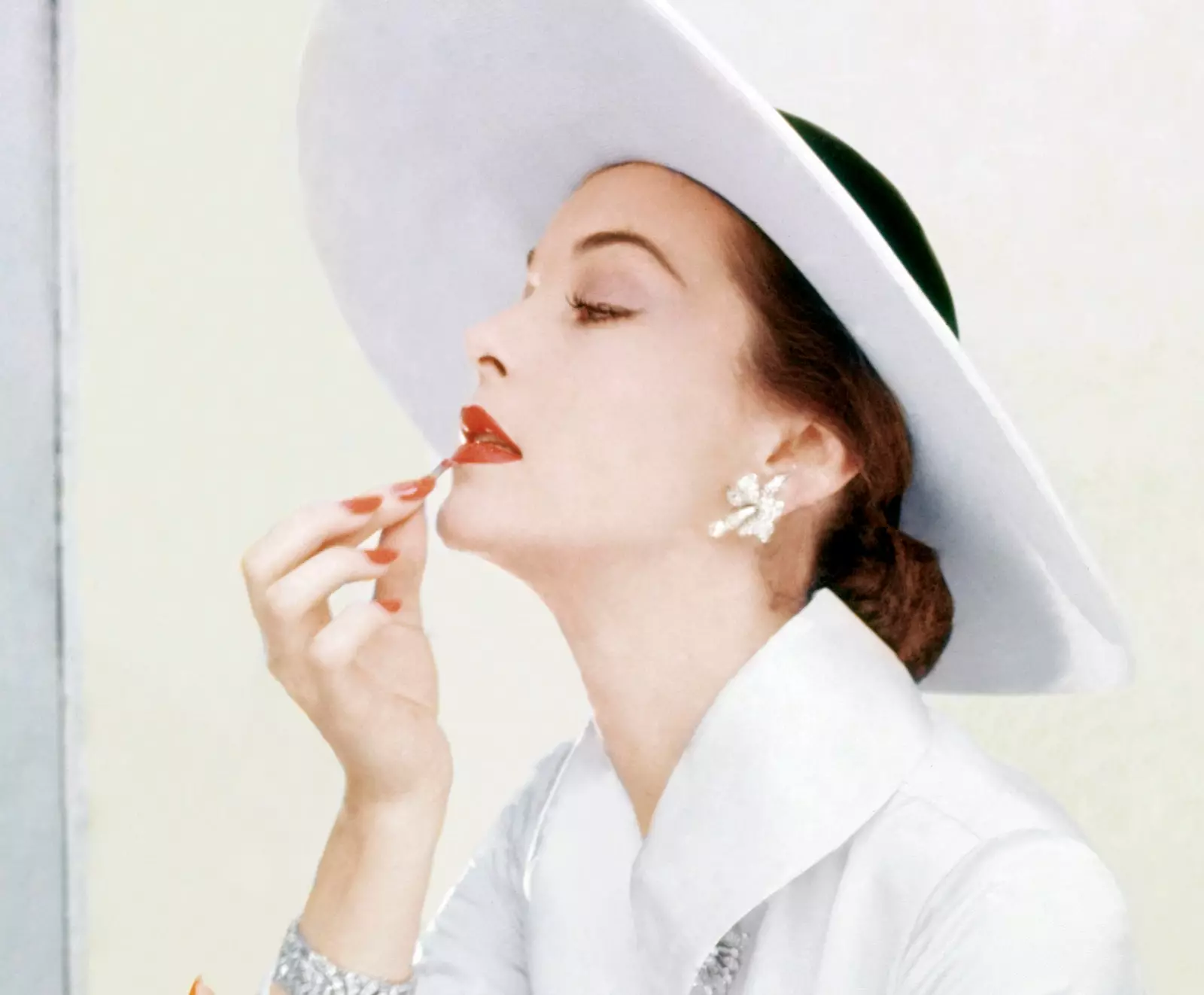 Modello che indossa giacca Ceil Chapman cappello John Fredericks e gioielli Van Cleef Arpels.